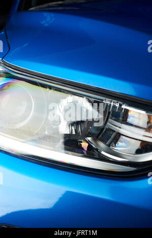 Front view of the LED headlights modern blue car on black background ...