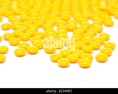 Yellow sugar coated tablets pills on white background with copy space ...