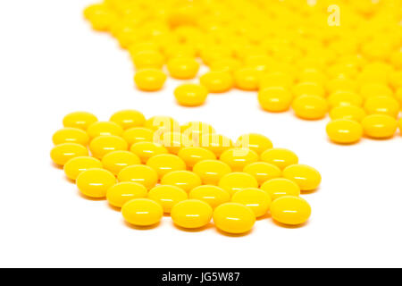 Yellow sugar coated tablets pills on white background with copy space ...