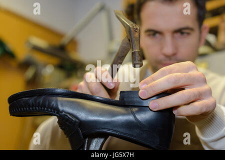 shoemaker hammering on a shoe in workshop Stock Photo - Alamy