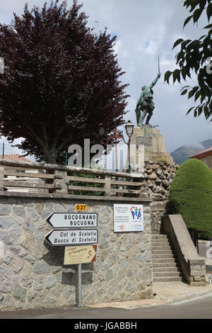 A statue of a man holding a sword is in front of a building with a sign ...
