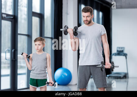 Boy training with dumbbells together with coach at fitness center Stock ...