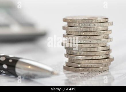 A stack of paper money and coins and a calculator on a light gray ...