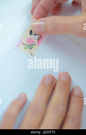 Putting a stamp on a letter Stock Photo - Alamy
