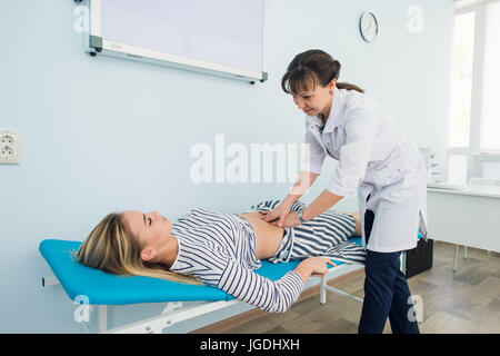 Doctor checking the stomach of one of her patients Stock Photo - Alamy