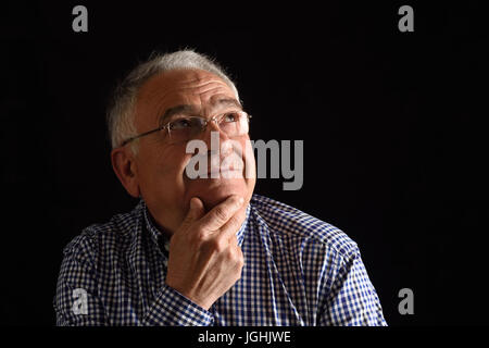 Pensative man on black background Stock Photo - Alamy