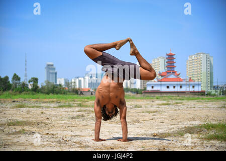 An Indian man doing Yoga poses at summer, with cityscape background ...