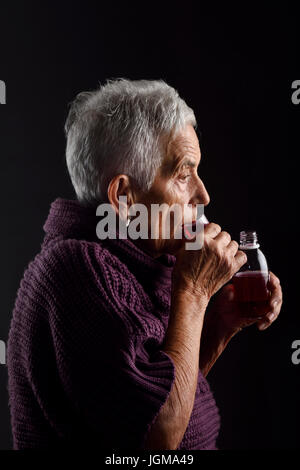 Senior woman taking cough syrup Stock Photo - Alamy