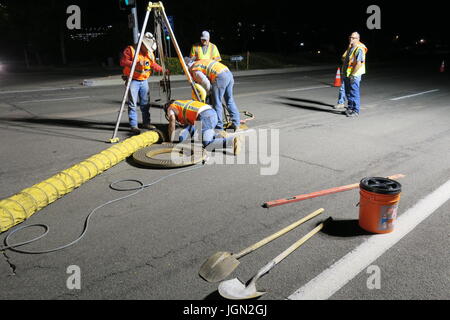 Men working on street sewer manhole at night Stock Photo - Alamy