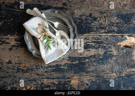 Table setting with fresh rosemary and rustic silverware on dark wooden ...