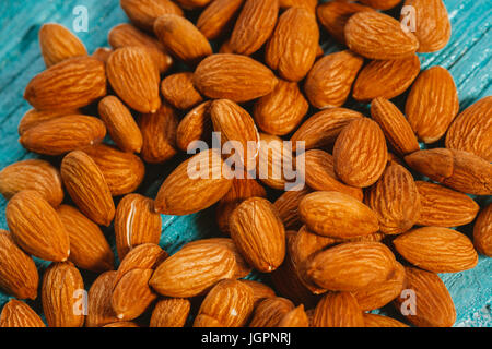 handful of almonds on a blue wooden background Stock Photo - Alamy