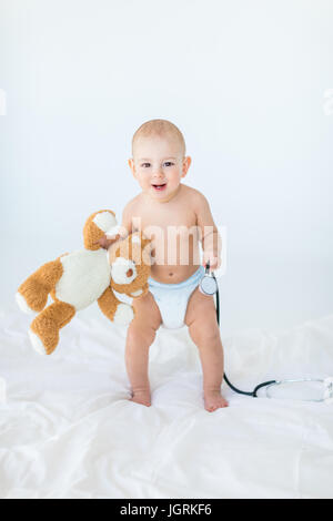 Adorable caucasian baby holding teddy bear sitting on sofa by christmas ...