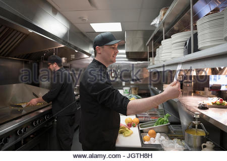 A commercial kitchen in a restaurant with cooks, food preparers and ...