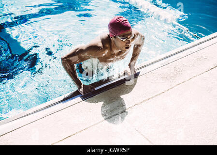 Swimmer climbing out of pool Stock Photo - Alamy