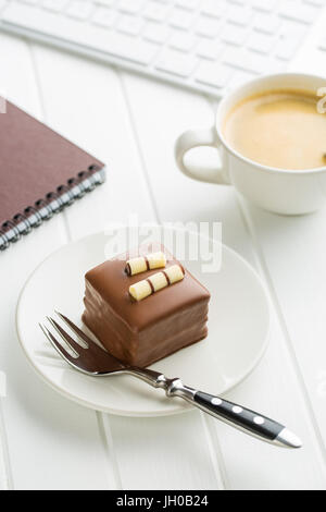 a notebook, a cup of coffee, a plate with a chocolate cake, a notebook ...