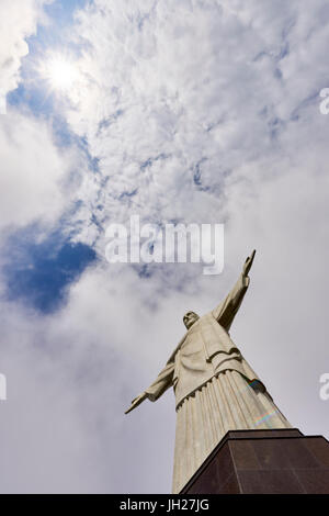 A low angle shot of the sun shining in gloomy cloudy sky above trees ...