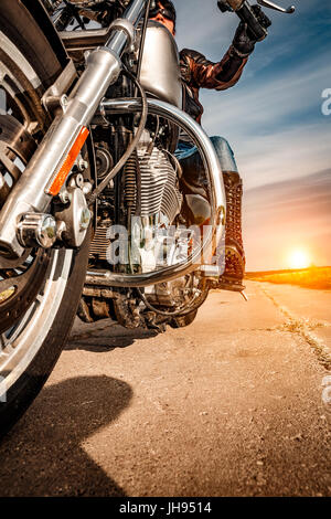 Biker riding a motorcycle. Bottom view of the legs in leather cowboy ...