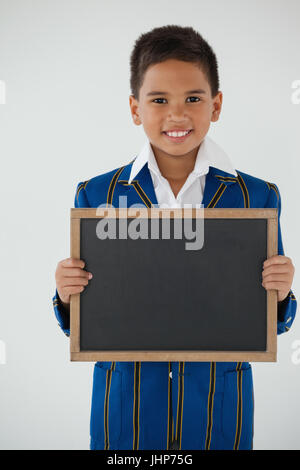 Portrait of schoolboy holding blank writing slate against white ...