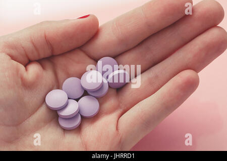 Pink, blue and purple tablets in three mortar and pestles held by ...