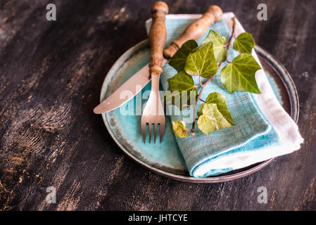 Rustic table setting with wild grape leaves on the plate on dark wooden ...