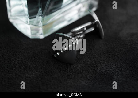 Silver cufflinks with rhinestones on a black background next to the ...