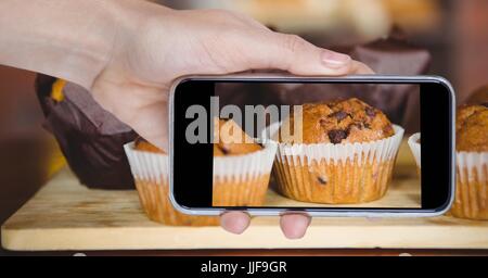 Digital composite of Hand photographing muffins through smart phone at ...