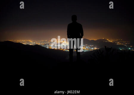 Silhouette of Cyclist with bike near big spruce tree at snow mountains ...