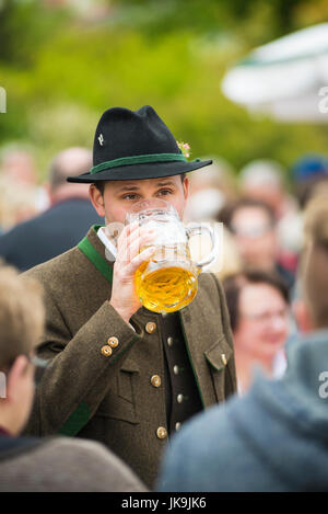 Young man in traditional German clothes with beer on white background ...