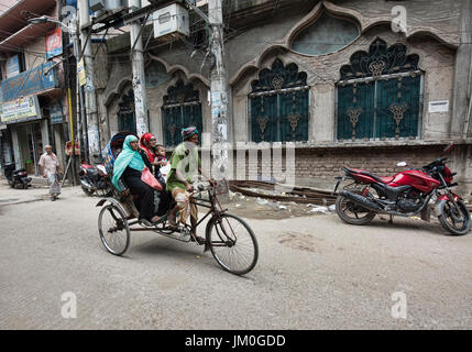 Muslim women travel by rickshaw in crowded street scene in city of ...