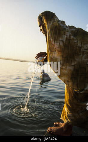 Hindu woman. Woman pouring water from a jug inside a Hindu temple ...