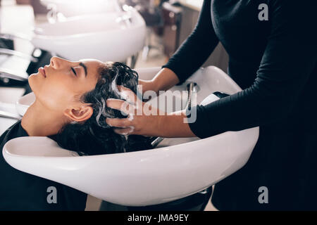 woman washing hair in hair salon with head backward in the sink having ...