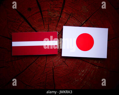 Latvia and Japan flag waving in the wind against white cloudy blue sky ...