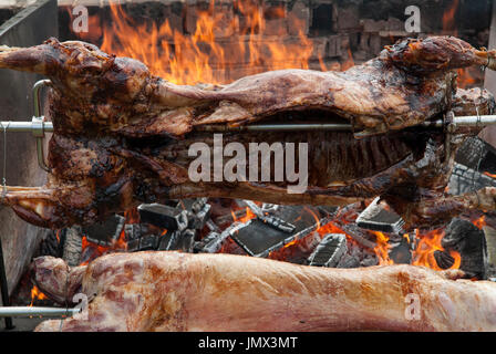 Whole lamb roasting on open spit Stock Photo - Alamy
