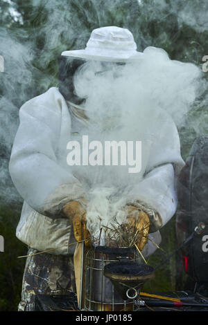 Jim Butler readies the smoke pot used to calm the bees when checking ...