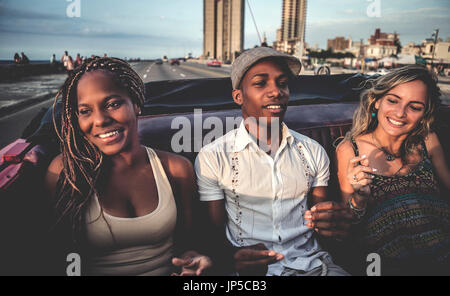 Two people riding through an urban environment in an open convertible ...