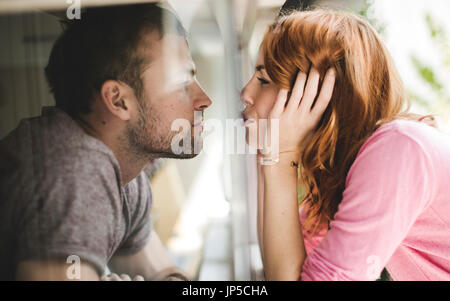 Couple kissing through glass window Stock Photo - Alamy