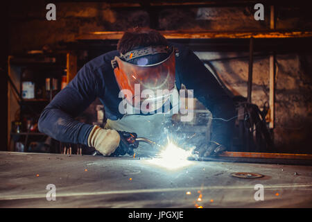 Young man welder at work. Welding mask on the face weld metal arc ...