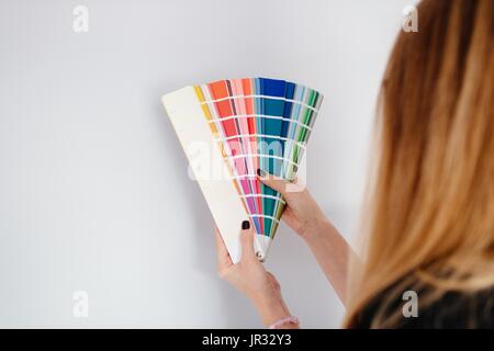 Woman choosing color for wall from swatches in room Stock Photo - Alamy