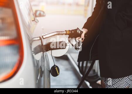 Woman refueling black automobile at gas station with blue fuel pump ...