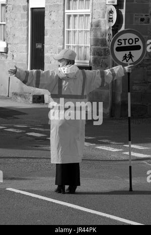 Lollypop lady, school traffic warden, with stop sign at school crossing ...