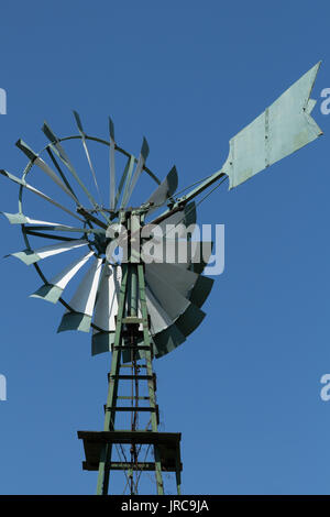 The metal blades and tail vane of a farm windmill that pumps water from ...