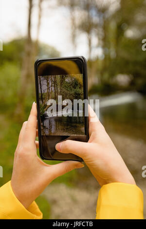 Woman clicking photos with mobile phone near lakeside Stock Photo - Alamy