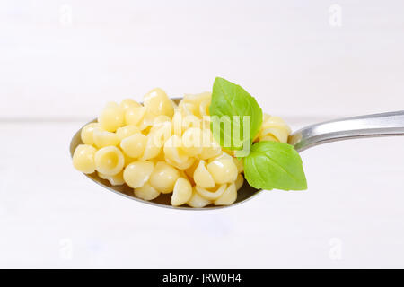 spoon of small pasta shells on white wooden background Stock Photo - Alamy