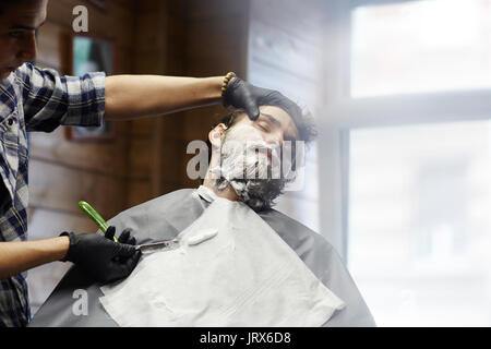 Self-employed barber shaving his client Stock Photo - Alamy