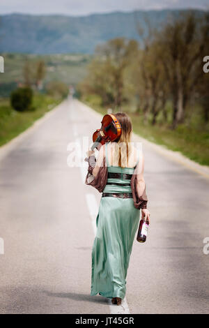 Beautiful female viola player walking along the highway Stock Photo - Alamy