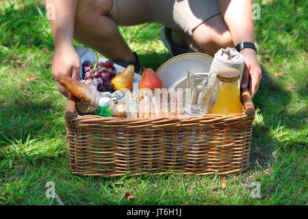 Wicker picnic basket with food and drink in a park. Summer picnic on ...