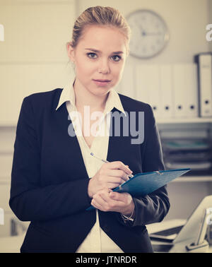 Attractive secretary writing instructions at workplace in office Stock ...
