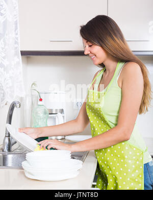 Smiling woman washing plates with sponge in domestic kitchen Stock ...