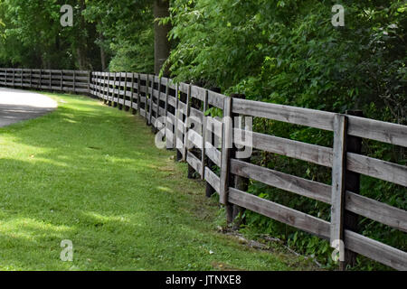 A crooked rustic fence with old wooden posts and barbed wire. In the ...