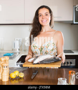 Happy girl with raw dorada fish on roasting pan at home kitchen Stock ...